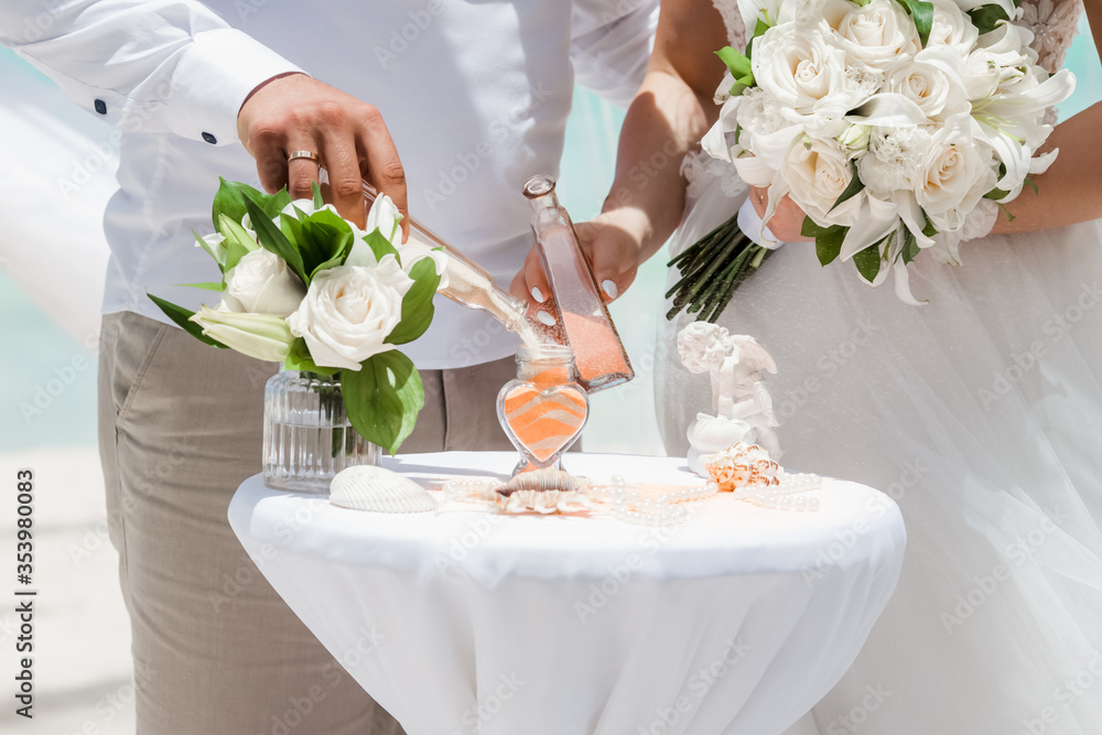 Bride and groom pouring colorful different colored sands into the ...