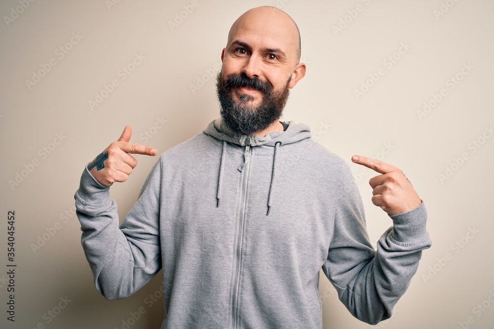 Handsome sporty bald man with beard wearing sweatshirt standing over ...