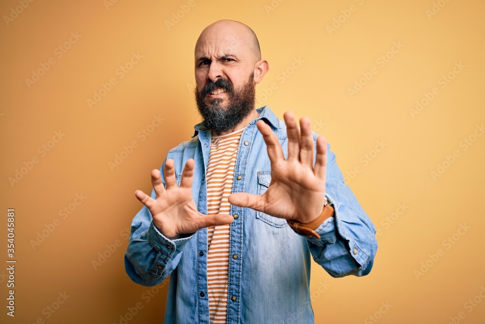Handsome bald man with beard wearing casual denim jacket and striped t ...