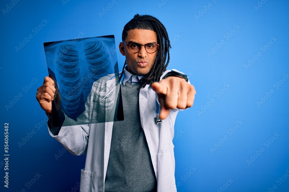 Young african american afro doctor man with dreadlocks holding chest ...
