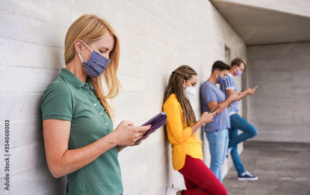 Young people wearing face safety masks using smart mobile phones while ...