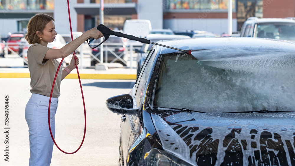 Caucasian young woman driver washing at manual car washing, cleaning ...