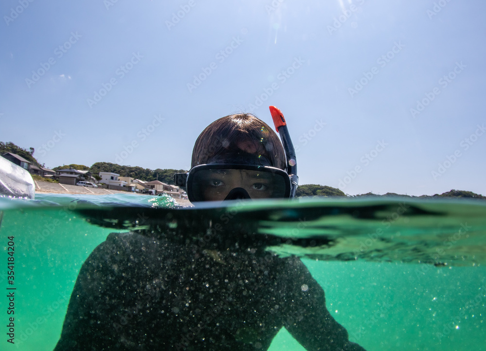 Diving in Japan, Teenage boy in a black with snorkel mask in a cave ...