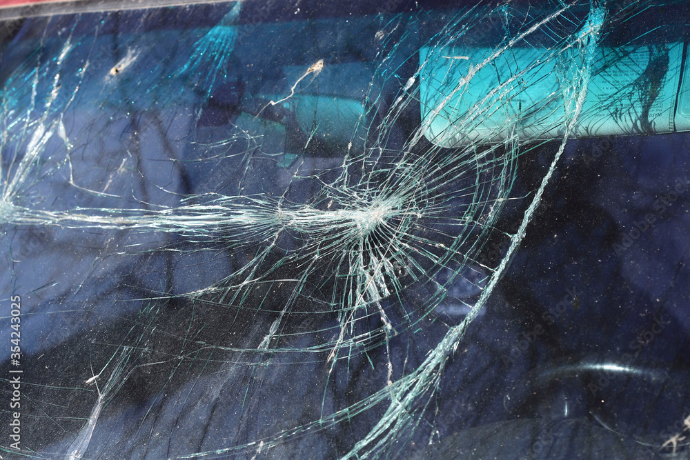 Blurred background of a broken car windshield. Closeup cracks and ...