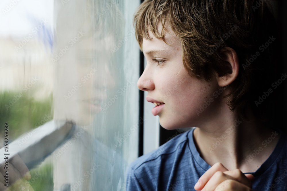 Cute 12 years old autistic boy looking through the window Stock Photo ...