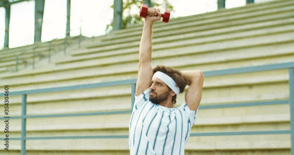 Portrait of handsome retro sportsman doing exercise on triceps with red ...