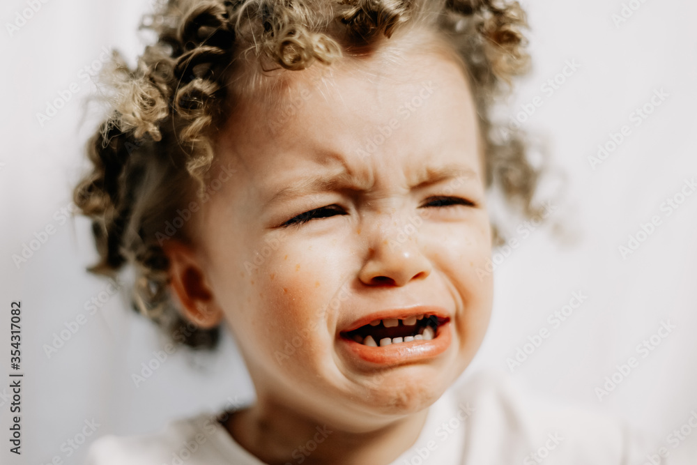 Foto de Little curly girl is crying very emotionally, face with tears ...