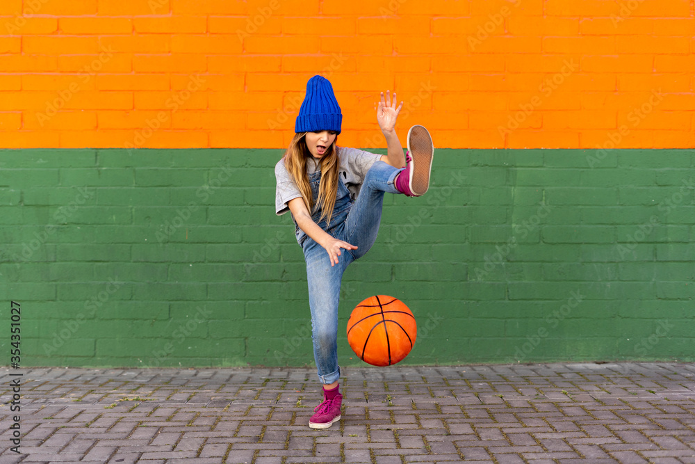 Young girl playing basketball, dribbling and lifting leg Stock Photo ...