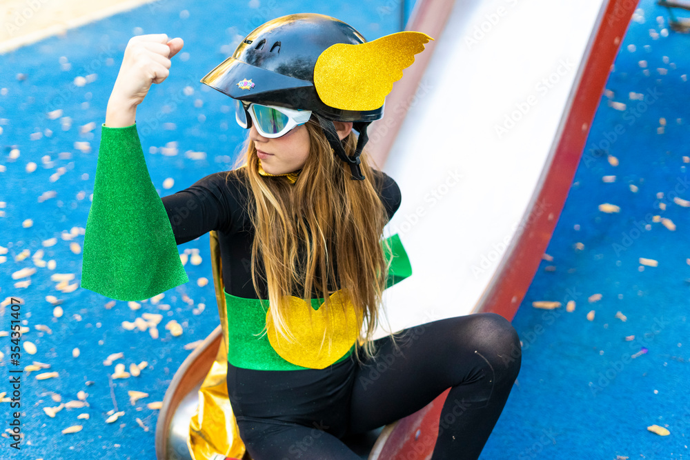 Girl in super heroine costume on playground slide flexing muscles Stock ...