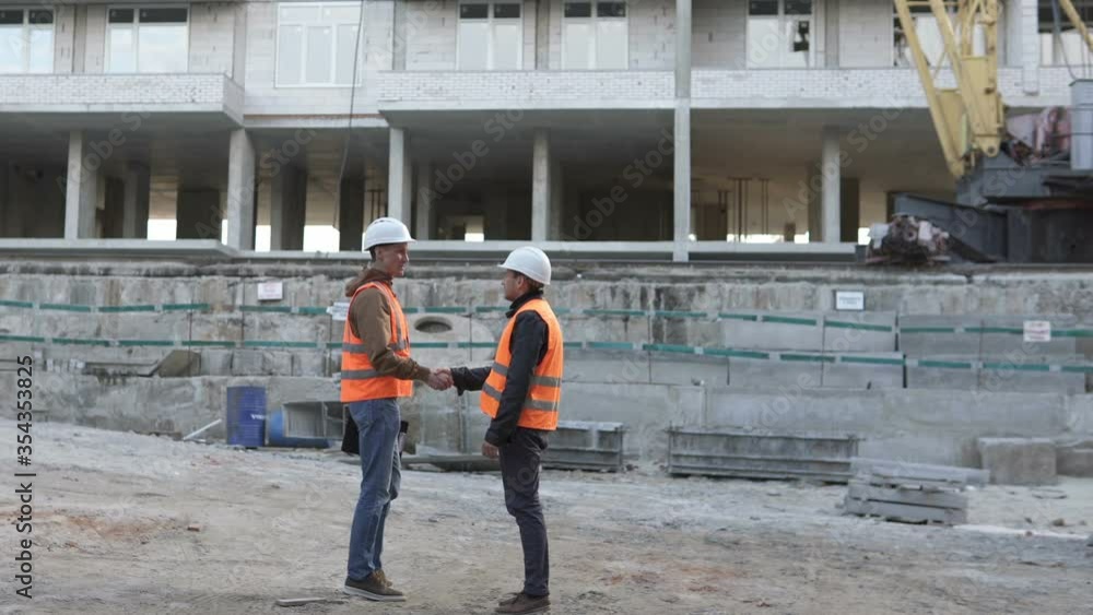 Friendly handshake of two builders at a construction site. Discussion ...