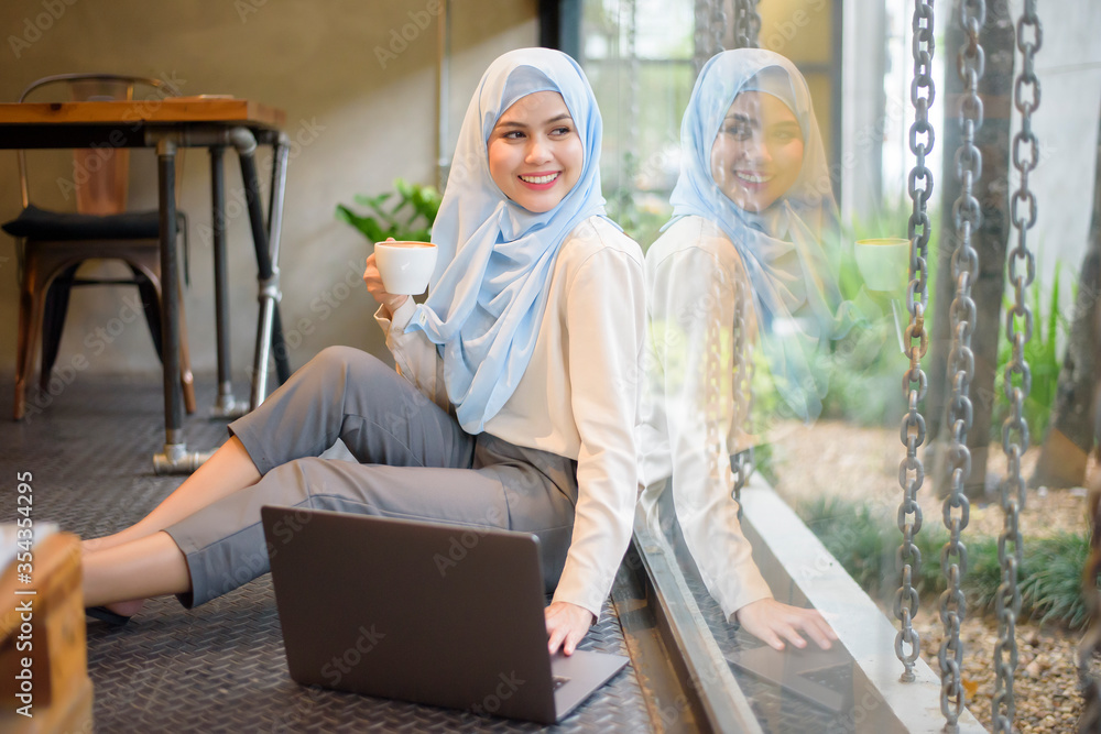 Muslim woman with hijab is working with laptop computer in coffee shop ...