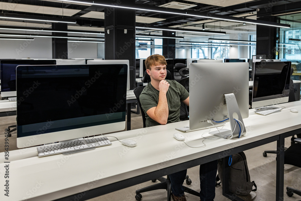 The concept of education, a young man sits at a computer, teaches ...