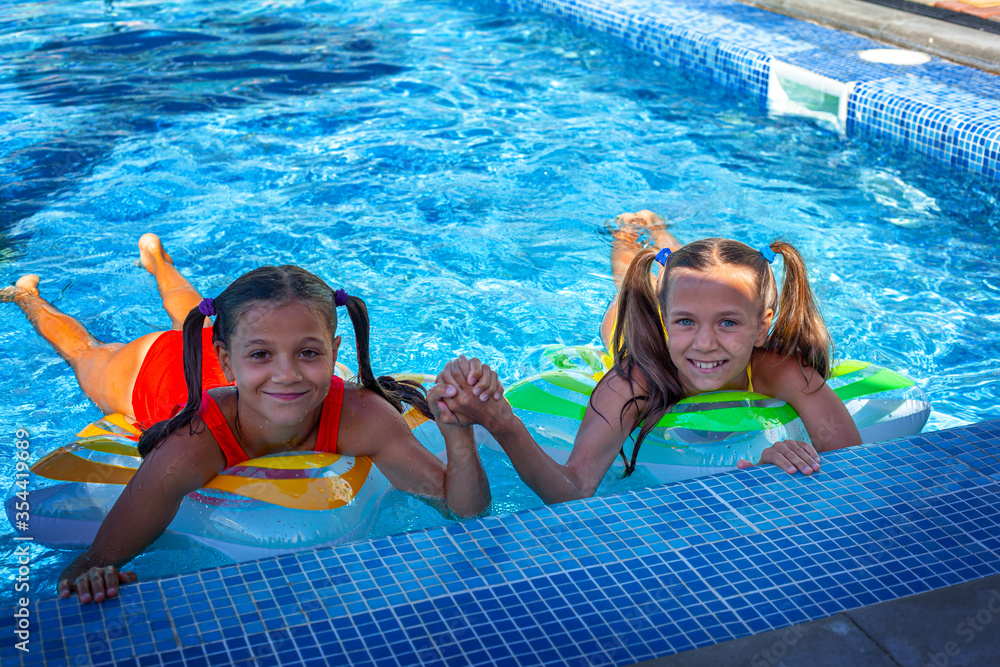Two tween girls playing, splashing, laughing and have fun in the blue ...