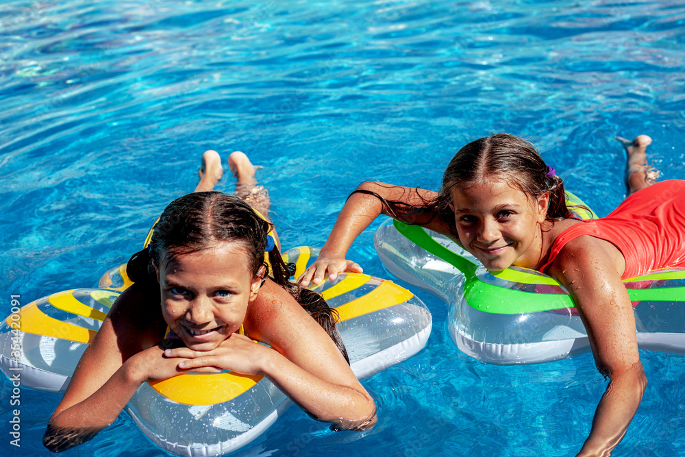 Two tween girls relaxing, laughing and have fun in the blue water of ...