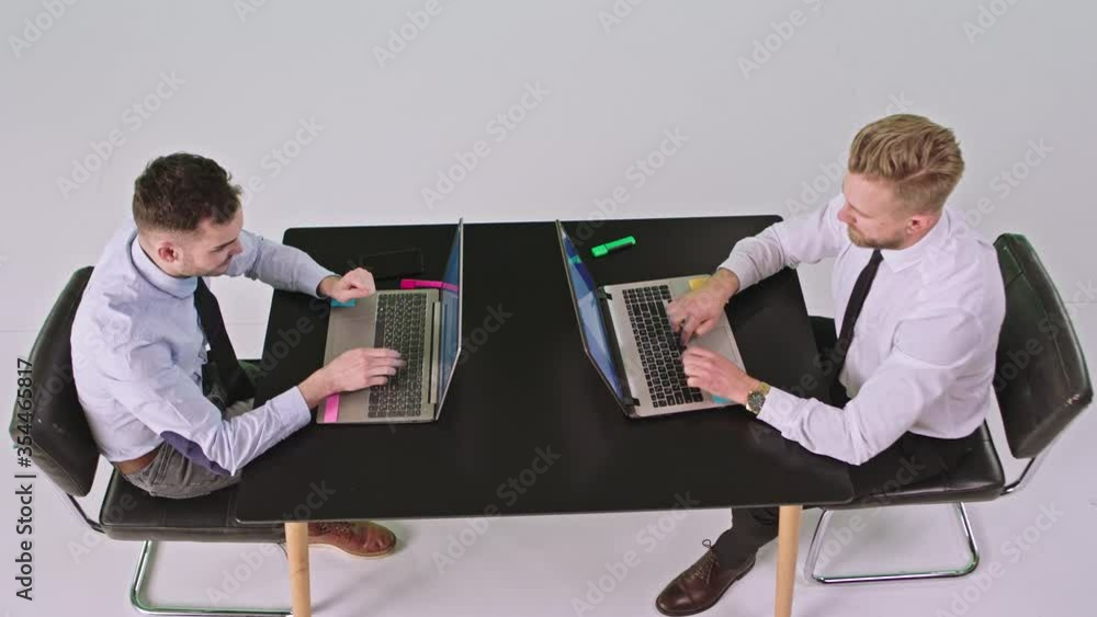 Concentrated two office workers men sitting at the same tablet in front ...