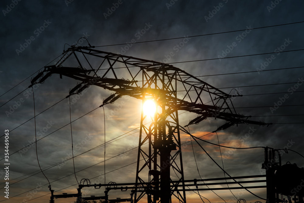 Power transmission tower with sun and back lit. Sun shines through a ...