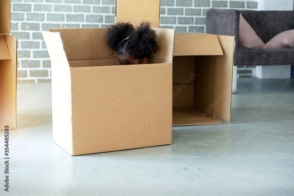 Little dark skinned girl sitting in cardboard box, child prepare for ...