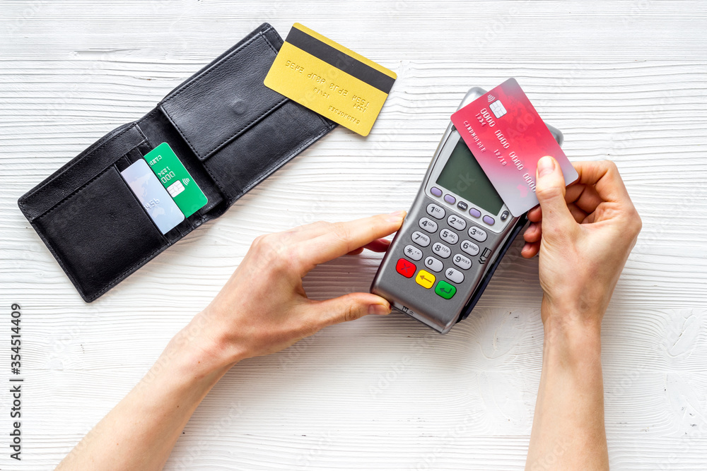 Payment by credit card. Hand hold card near terminal on white desk top ...