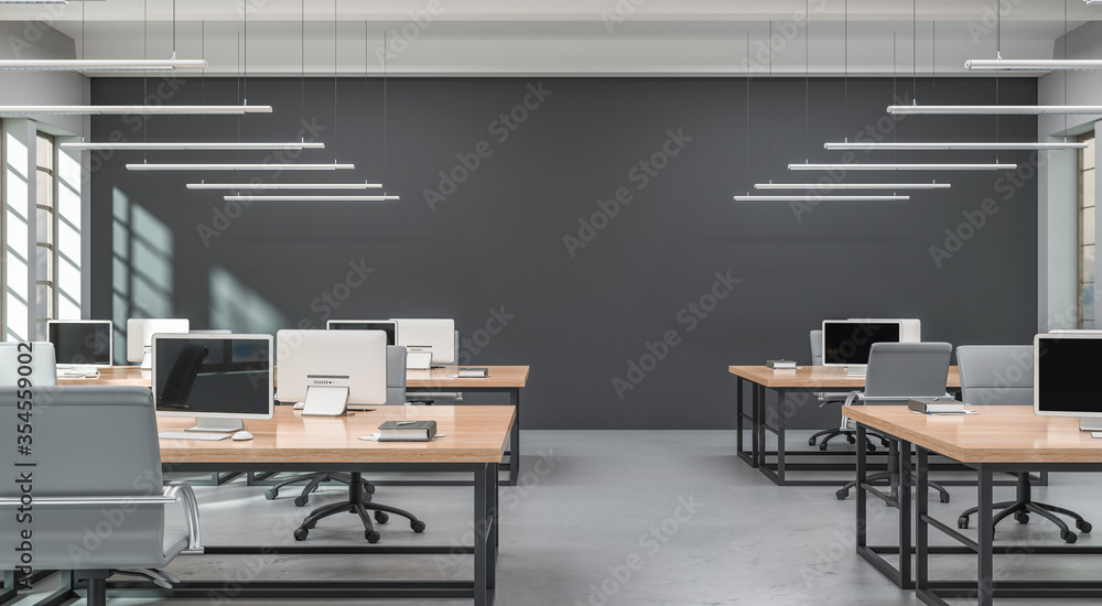 Side view of a modern office with a grey wall. Rows of tables, equipped ...