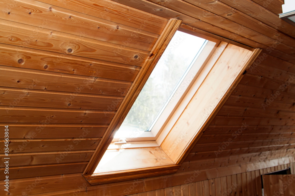 Open dormer window in wooden house in the attic. Room has sloping ...