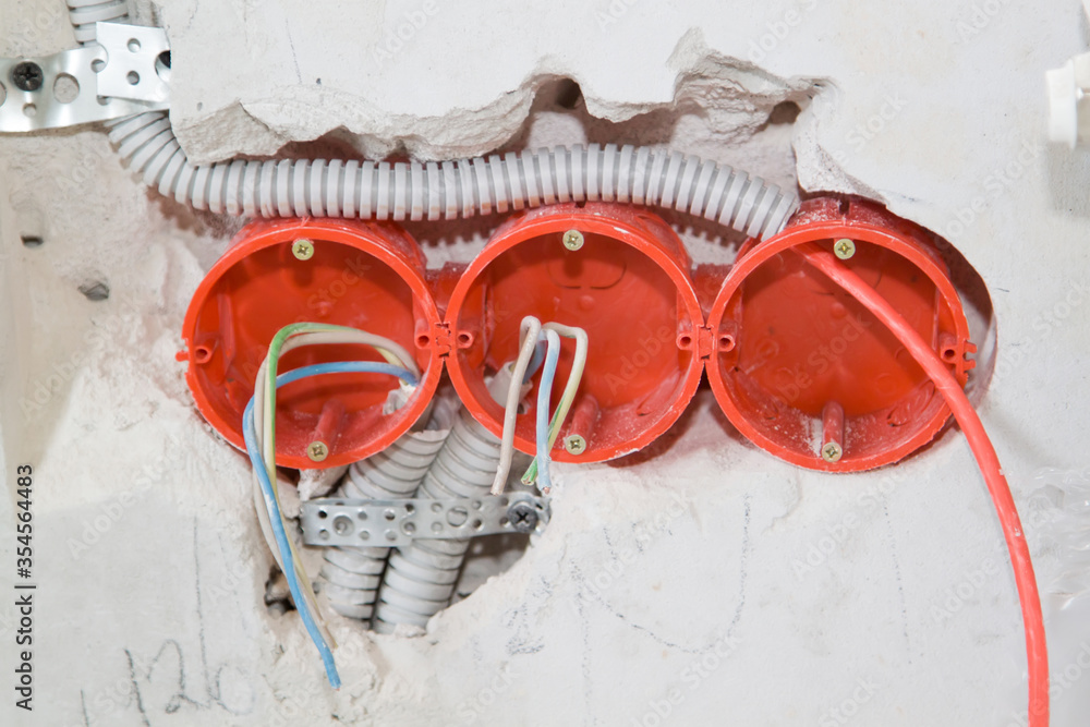 Protruding electric wires and cables in holes inside grey cement wall ...