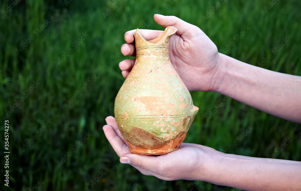 Ancient ceramic broken jug in the hands of student archaeologist, grass ...