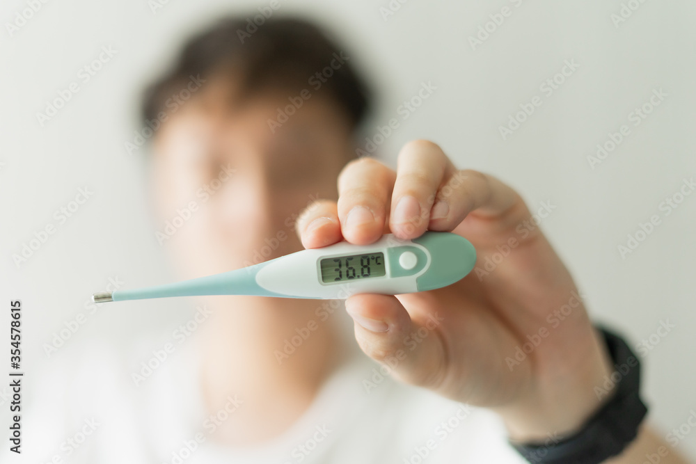 The young man measured his body temperature using a thermometer. Stock ...