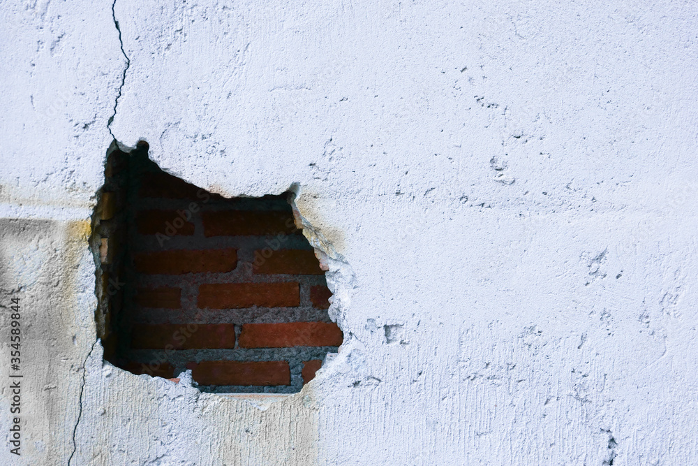Hole in broken wall and old bricks on white background. Large crack on ...
