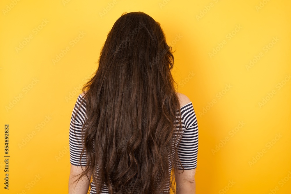 The back view of a girl with long straight wavy and shiny hair standing ...