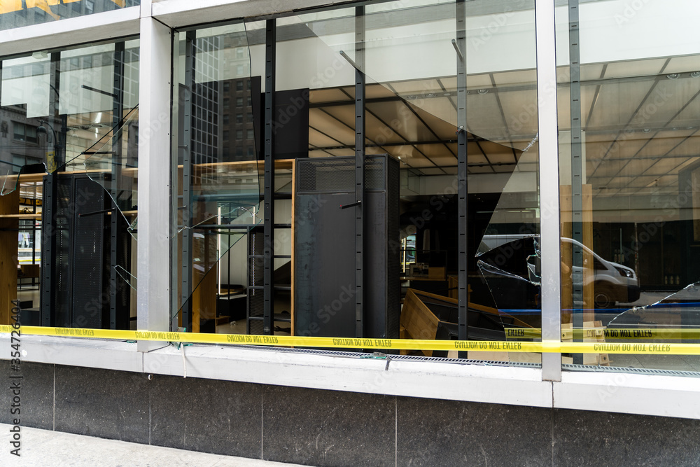 broken window with yellow strip "caution do not enter". damaged store ...