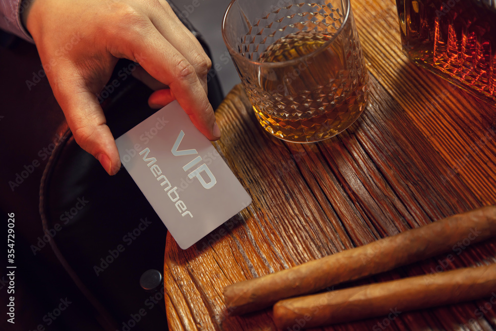 Man's hand puts VIP membership card on the table. Gentleman's hand puts ...