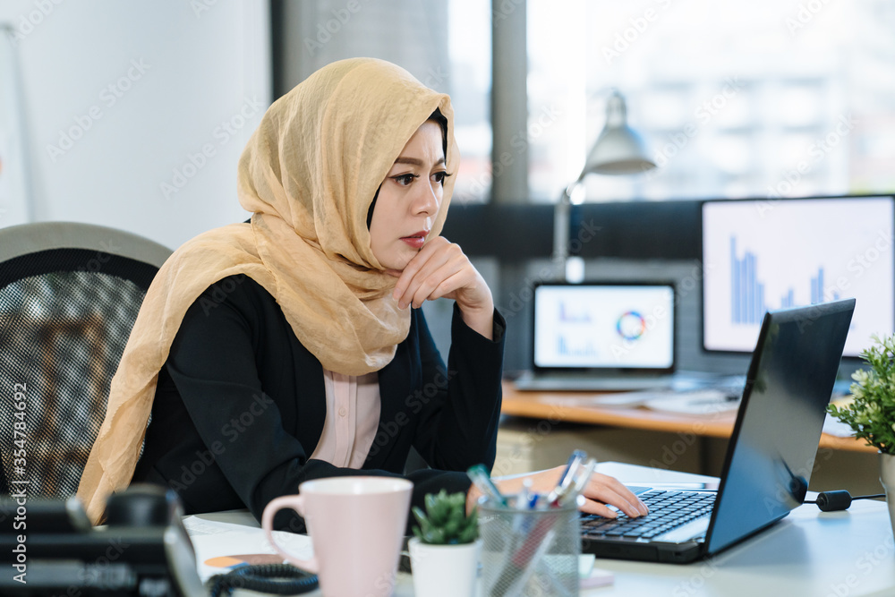 Thoughtful worried muslim businesswoman in black suit and hijab with ...