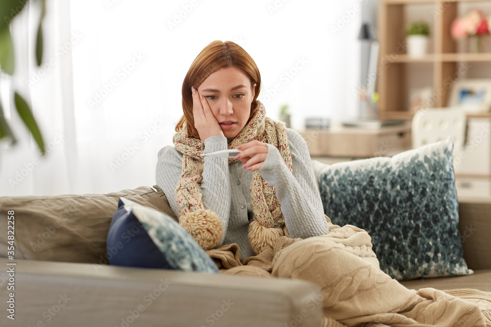 people, health and fever concept - sad sick woman in blanket measuring ...