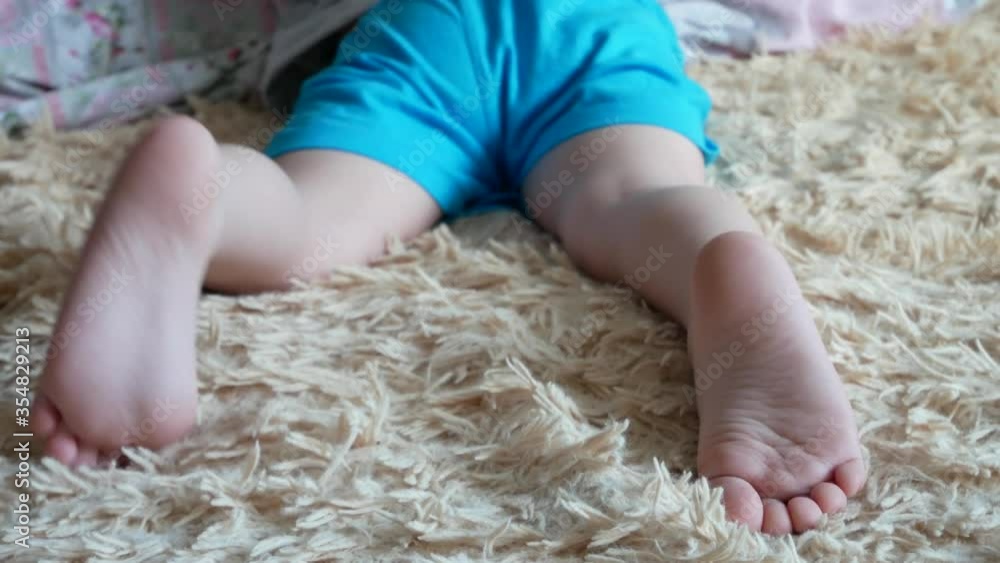 Two feet of a little boy lying on a soft plaid vídeo de Stock | Adobe Stock
