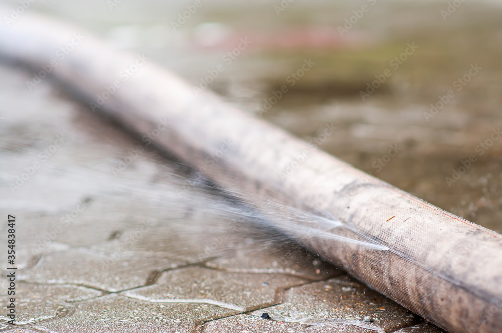 Leaky fire hose to extinguish fire, water is spilled, a ruptured hose ...