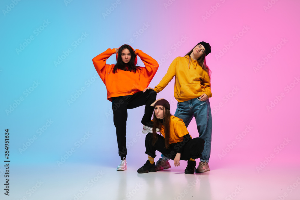 Flexible. Sportive girls dancing hip-hop in stylish clothes on colorful ...