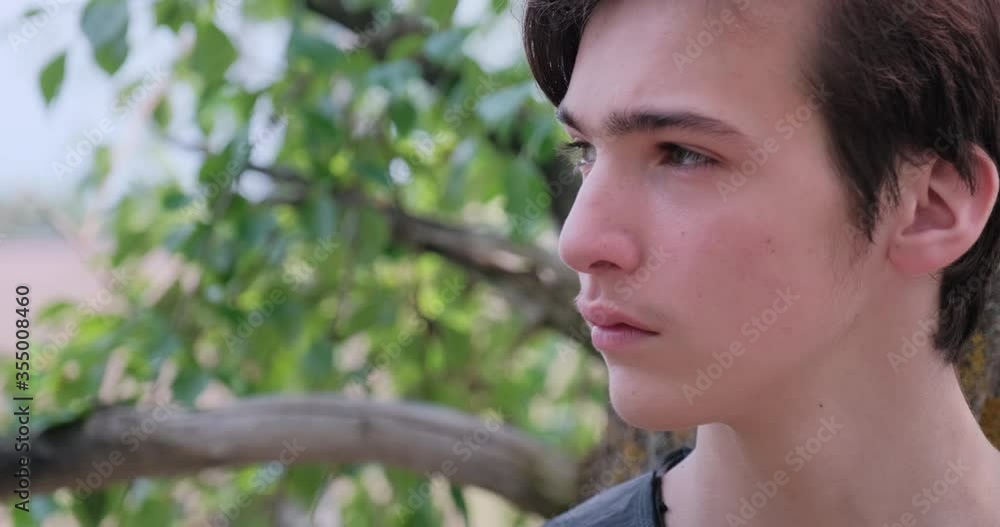 Young sad man is looking away. Unhappy alone young teenager, outdoors ...