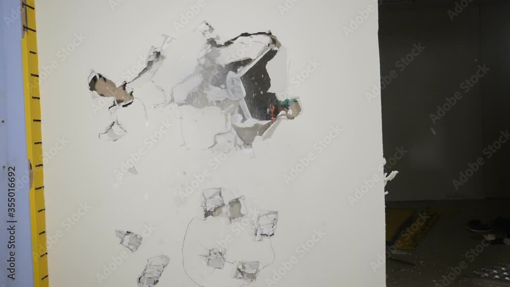 Wall made of gypsum cardboard being destroyed. Worker in uniform ...
