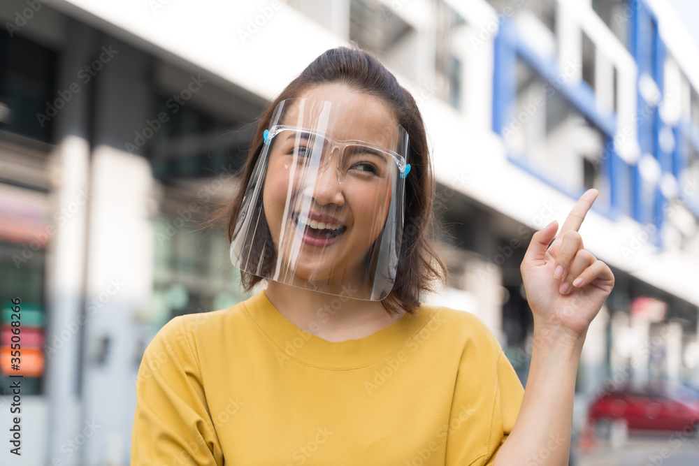 Portrait happy woman wile wearing a face shield for protection from ...