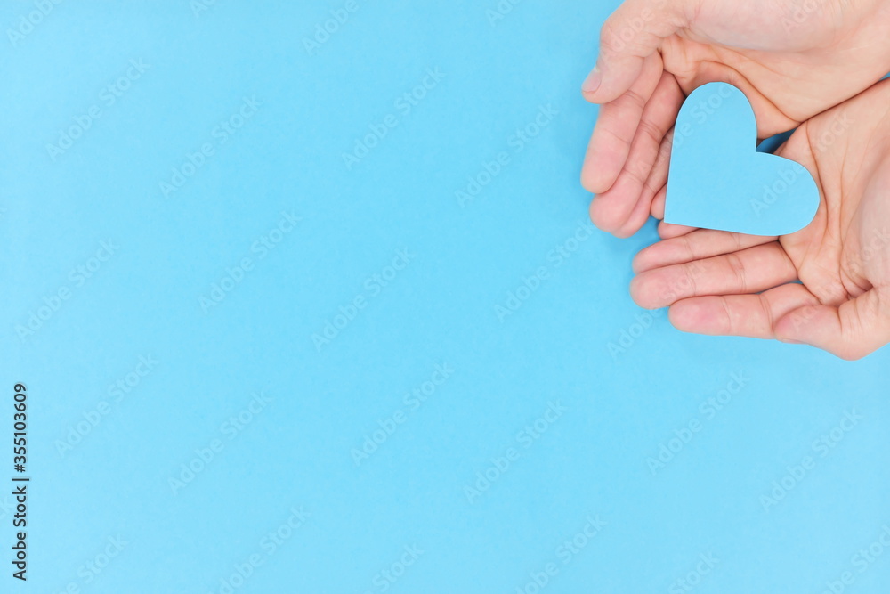 Cupped hands holding a blue heart in blue background. Charity, pure ...