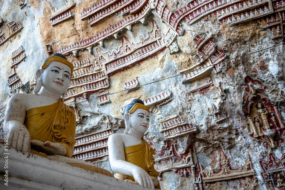 Small figurines carved on the rock walls at Kaw Goon caves and white ...