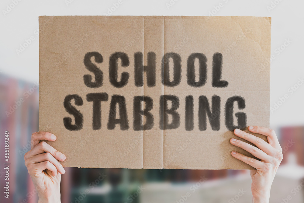 The phrase " School stabbing " on a banner in men's hand with blurred ...