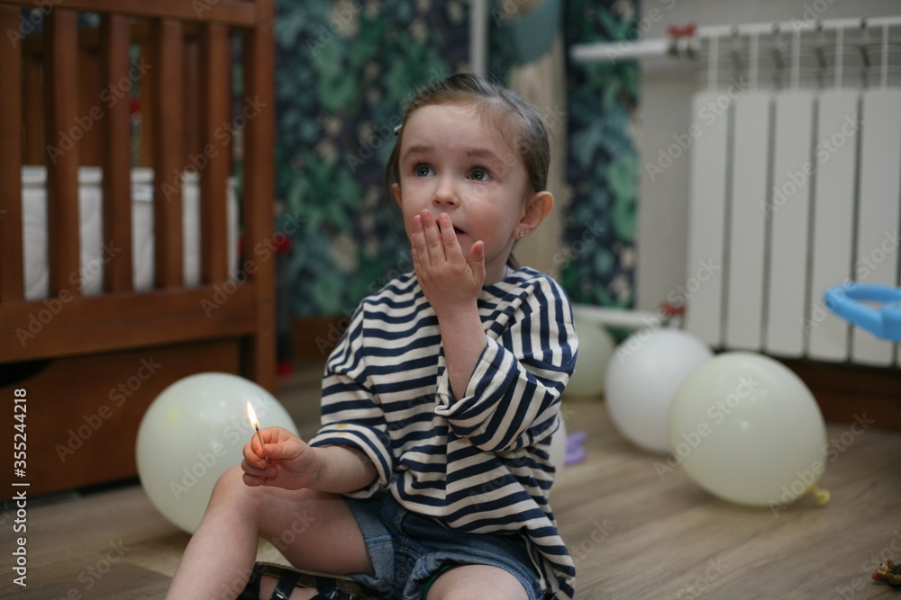 A child plays with fire when parents are not at home. A match burns in the hands of a little ...