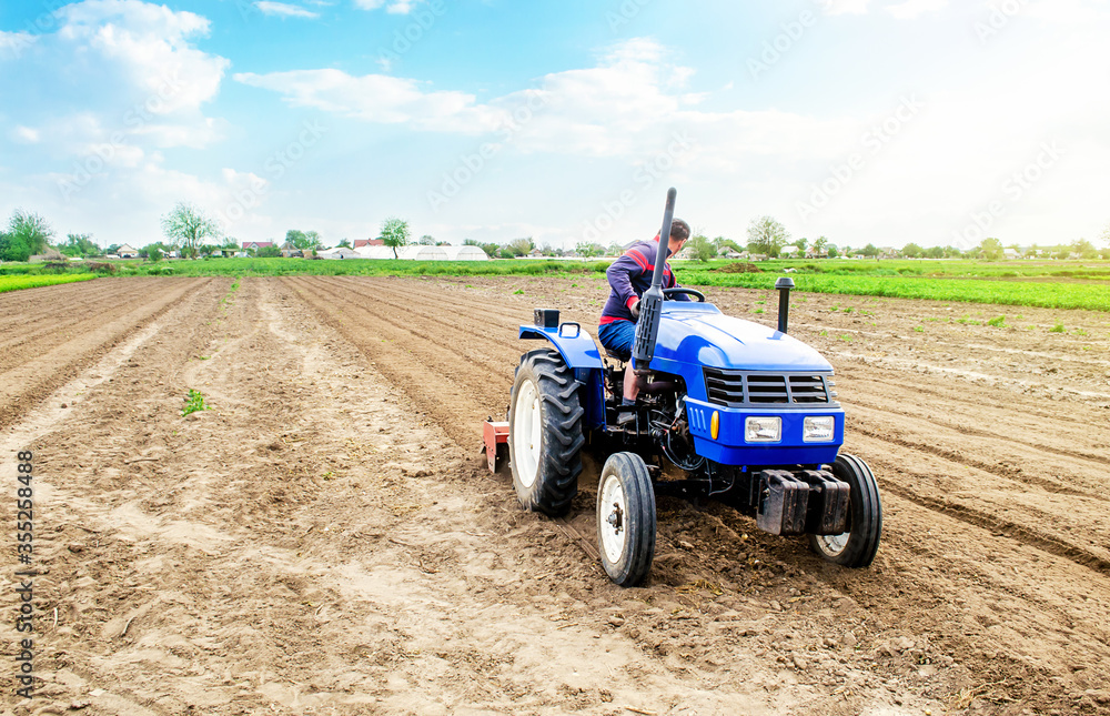 A farmer riding a tractor on a farm field. Farming and work in the ...