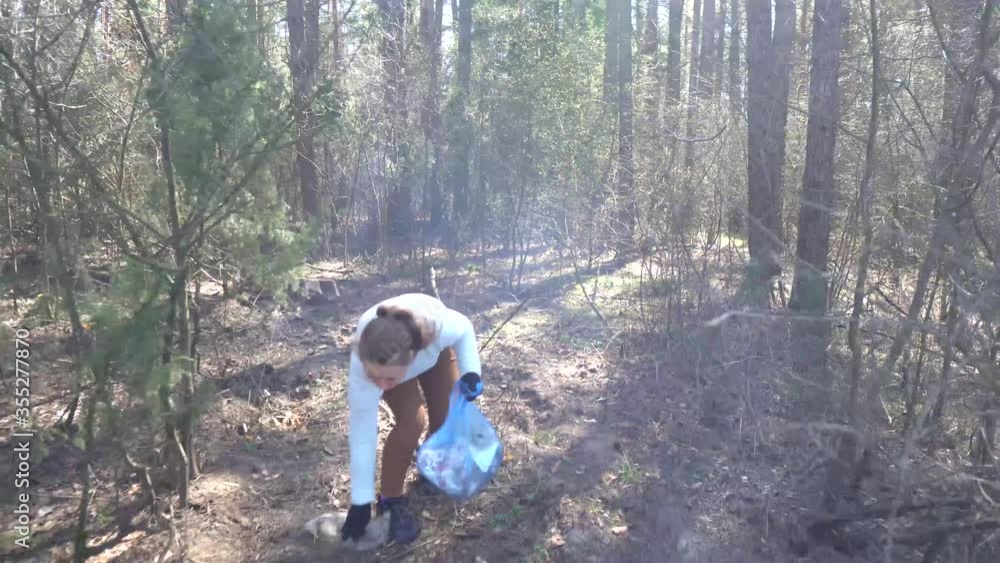 Video „A girl collects garbage in the forest. Environmental pollution ...