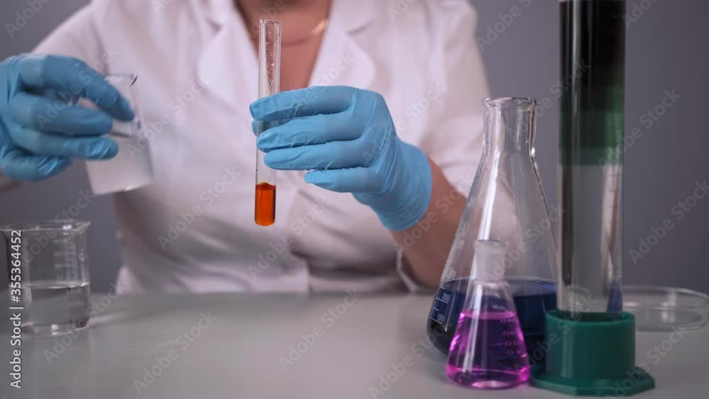 A female scientist mixes liquids in a test tube and gets a visual ...