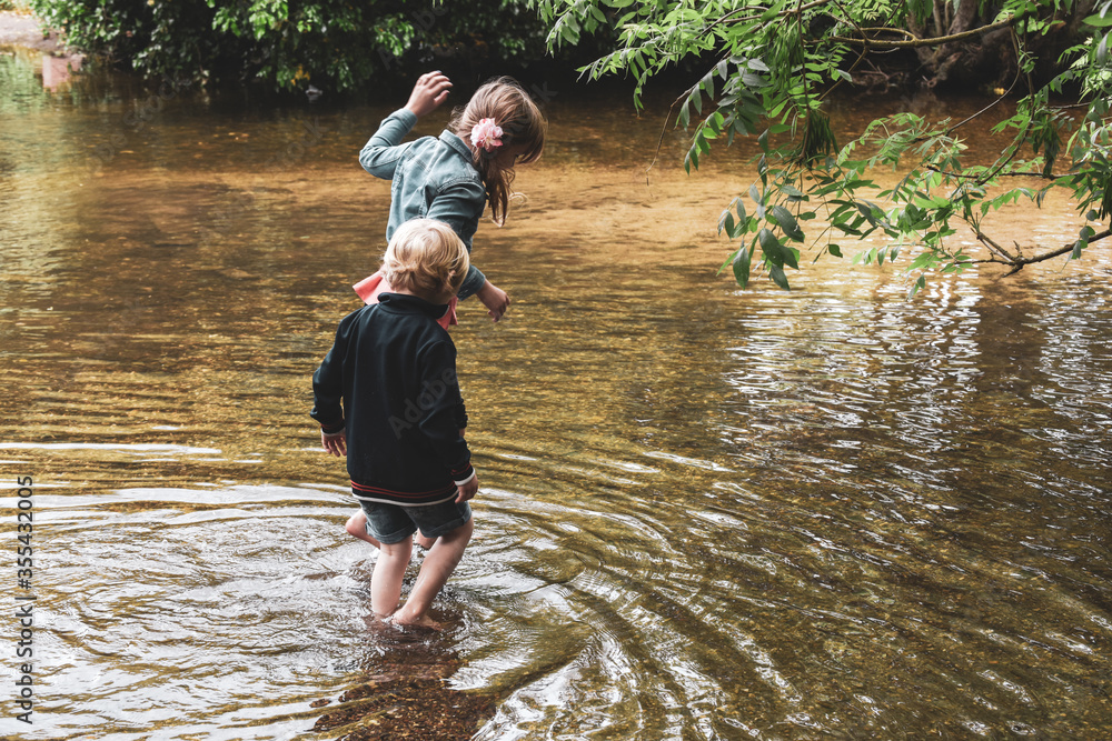Children playing outside in a shallow stream paddling in the water foto ...
