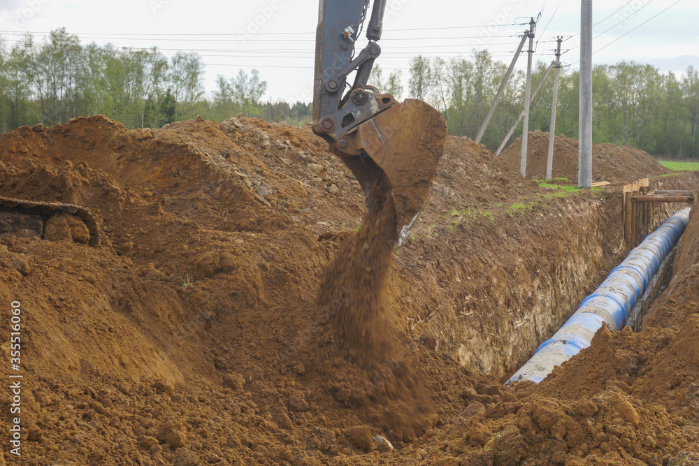 From the large bucket of a crawler excavator, the earth pours out into ...