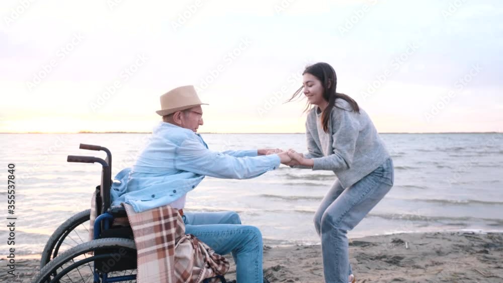 Happy young granddaughter supports, raises old smiling disabled ...