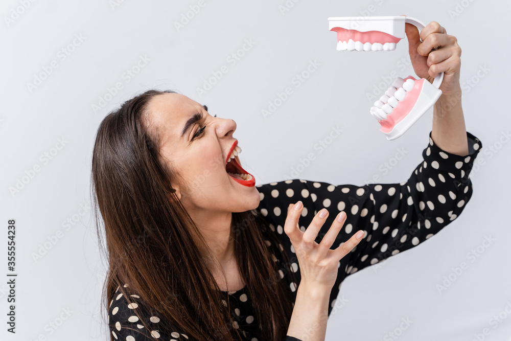 Funny girl toing with dental jaw on white background. Opened plastic ...